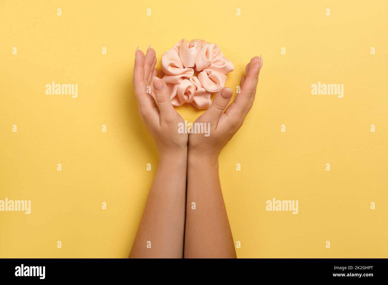 Female hand with silk scrunchy on yellow background Stock Photo - Alamy