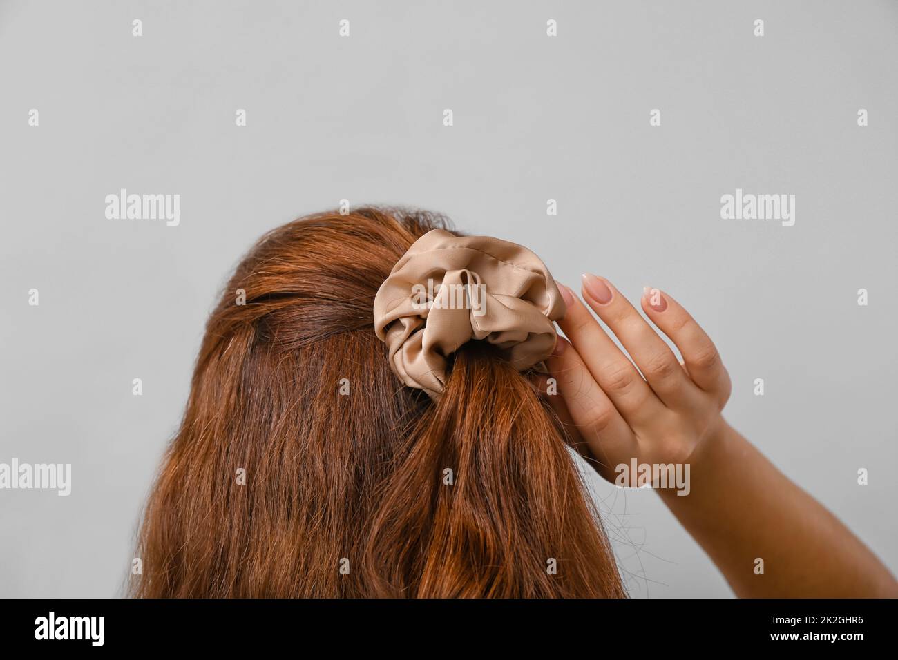 Woman adjusting silk scrunchy on light background, closeup Stock Photo ...