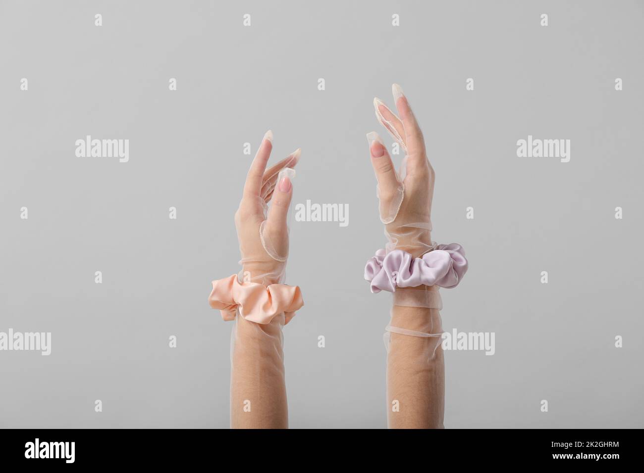 Female hands in gloves with silk scrunchies on light background Stock ...