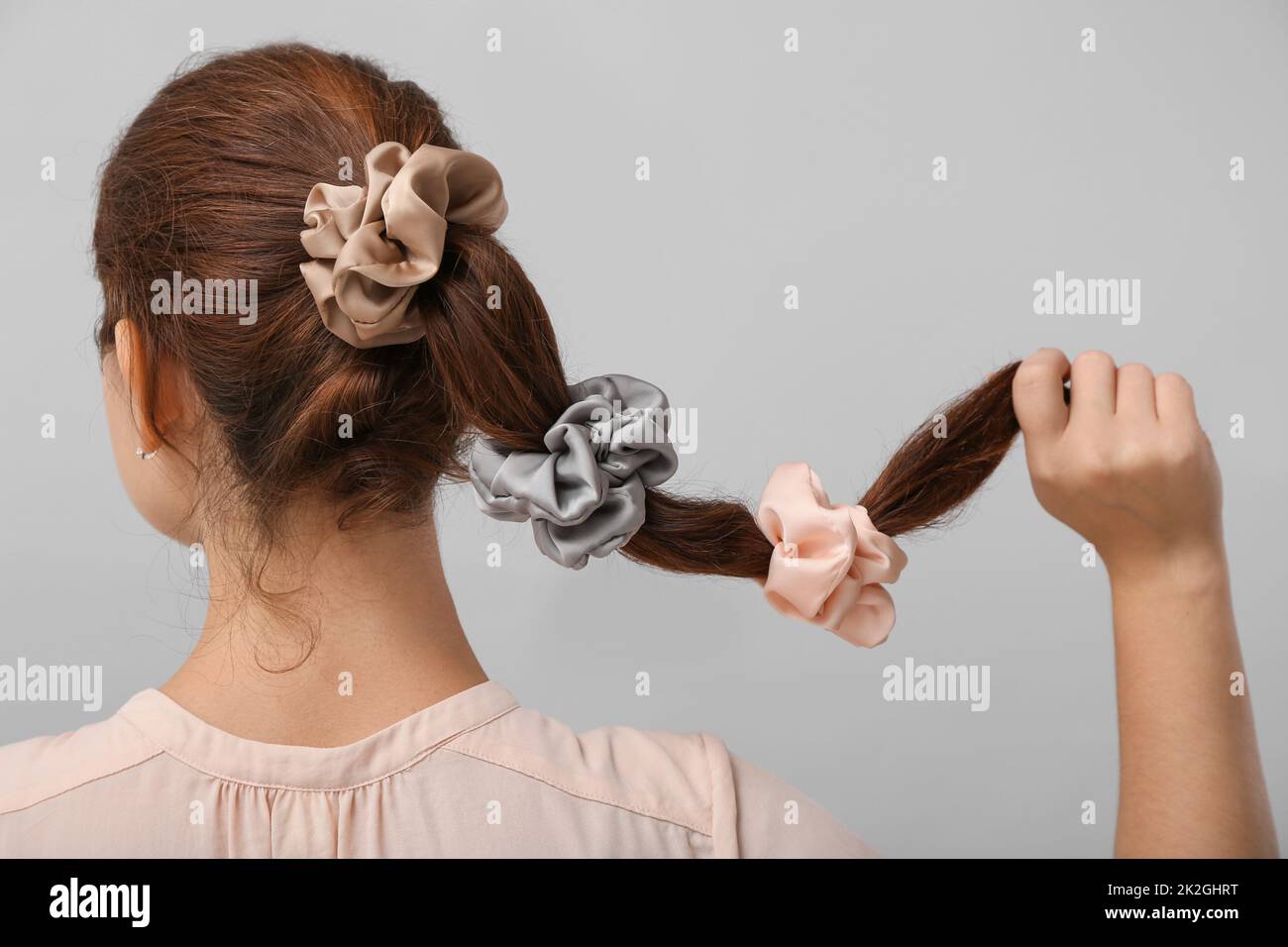 Woman with silk scrunchies on ponytail against grey background Stock ...
