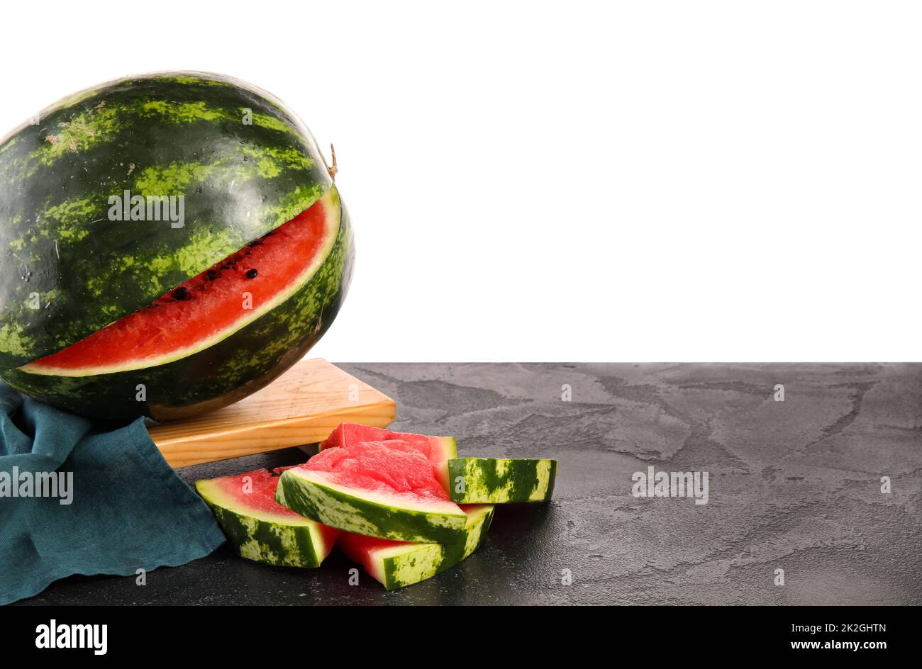 Slices of ripe watermelon and napkin on table against white background ...
