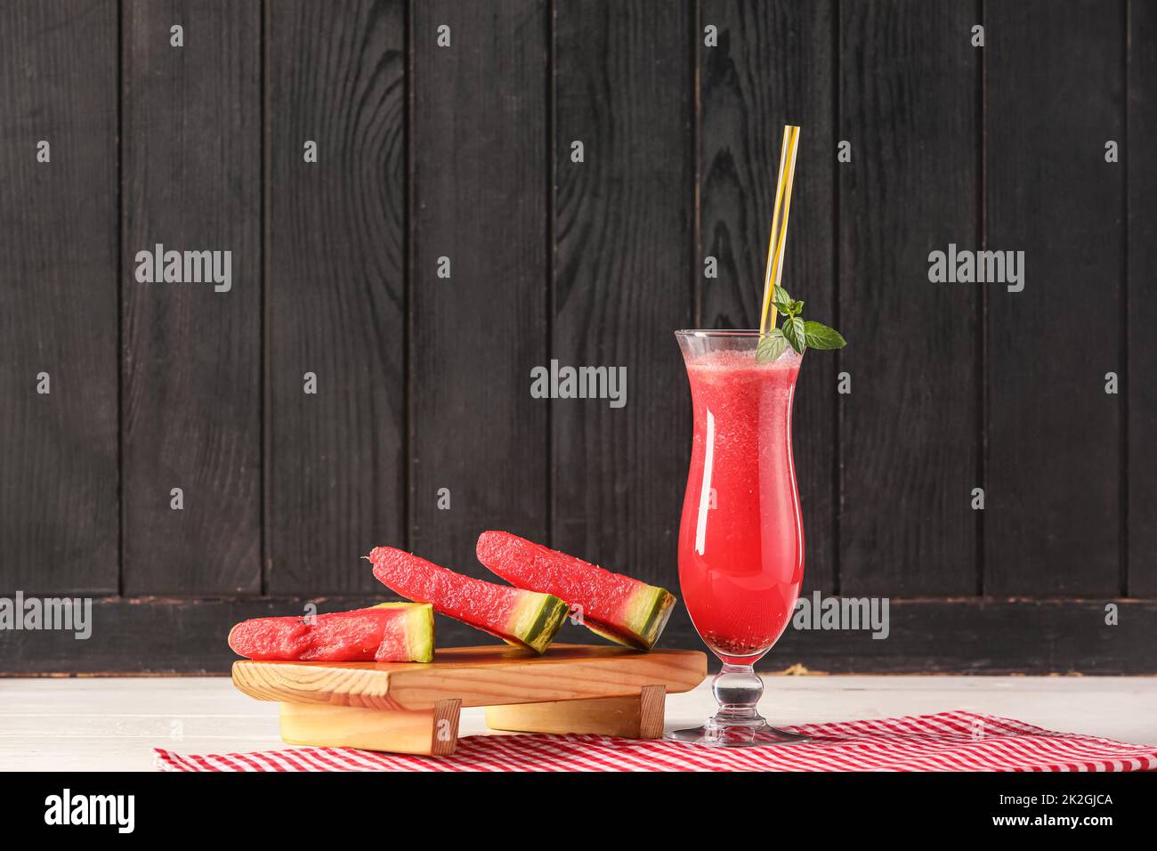 Glass of cold watermelon fresh on table against dark wooden background ...