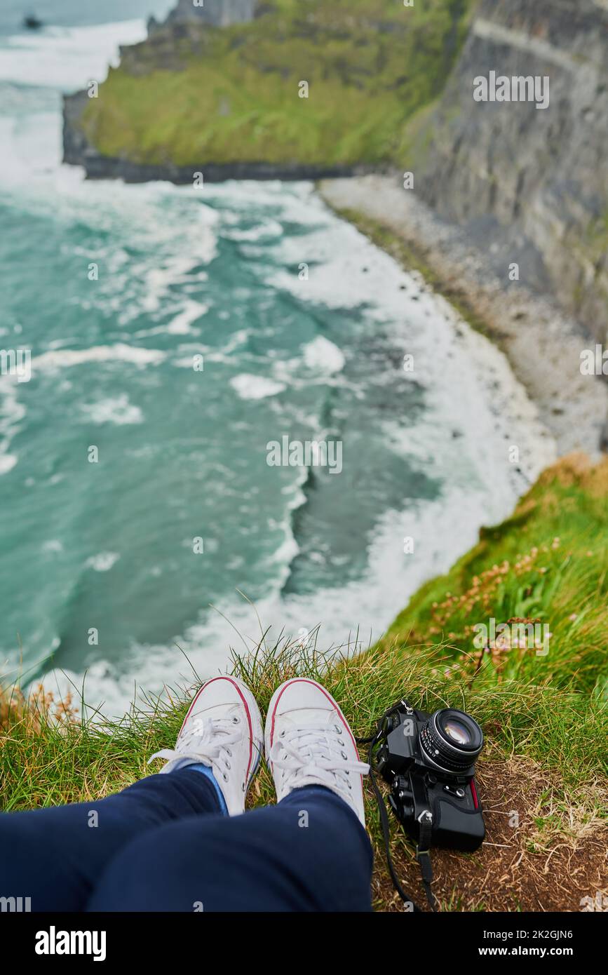 Looking down at the world. High angle shot of an unrecognizable woman sitting on cliff and ...