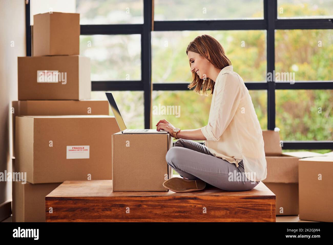 Setting up her forwarding address online. Shot of a young woman using a ...