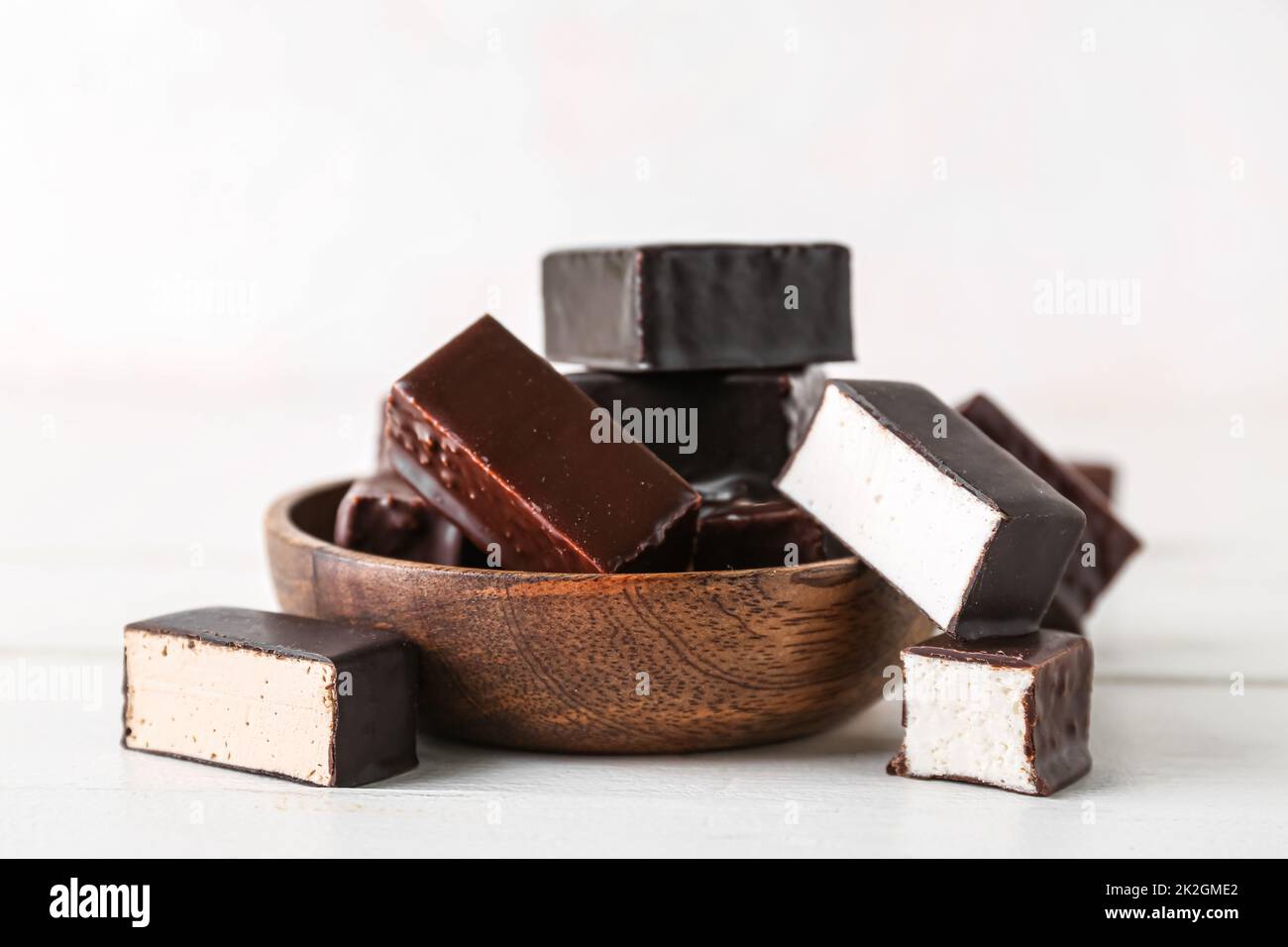 Bowl of tasty bird's milk candies on table against white background ...