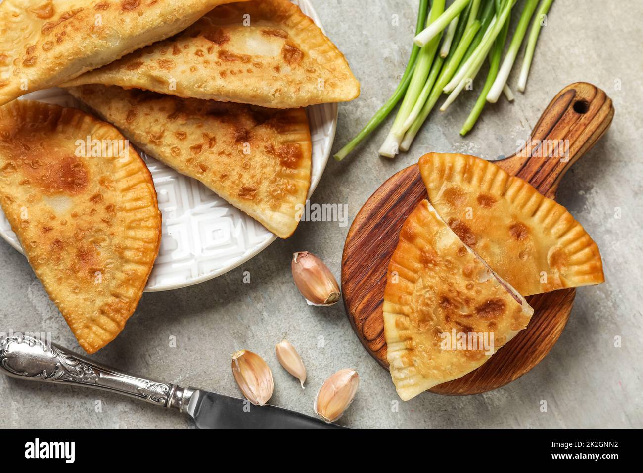 Plate and board with tasty chebureks on grunge background, closeup ...