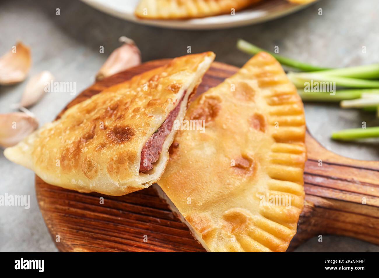 Wooden board with tasty chebureks on grunge background, closeup Stock ...