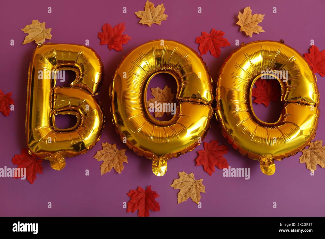 Word BOO made of balloons and fallen leaves on purple background ...
