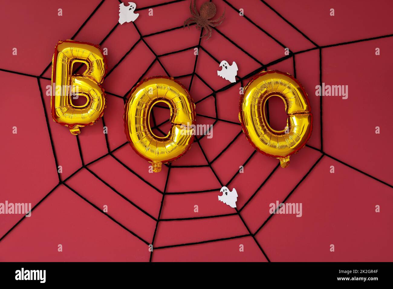 Word BOO made of balloons, spider web and paper ghosts on red wall ...