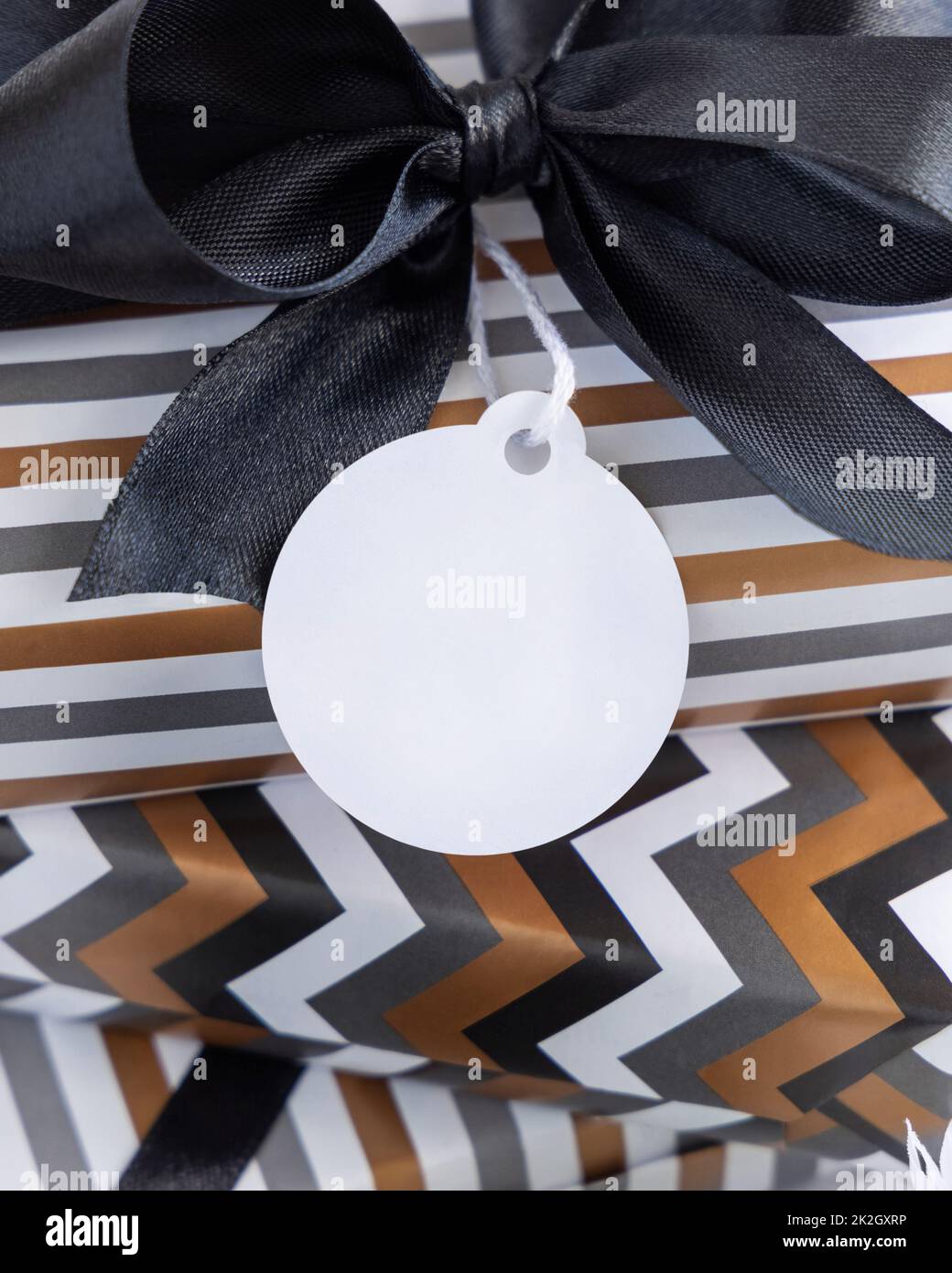 Wrapped present with round blank gift tag and black bow close up, label ...