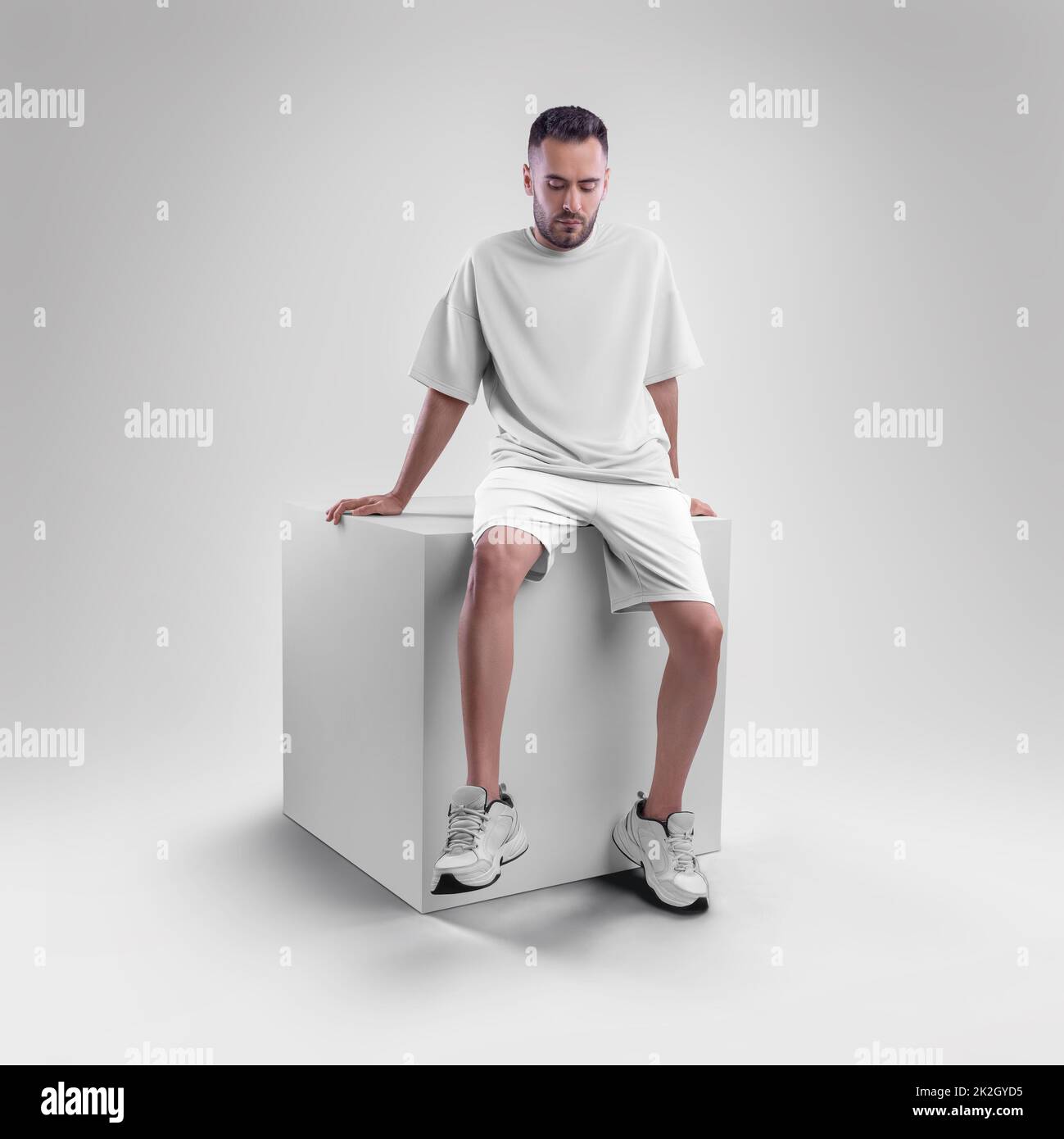 Mockup of white men's oversized t-shirt with shorts on a man sitting on ...