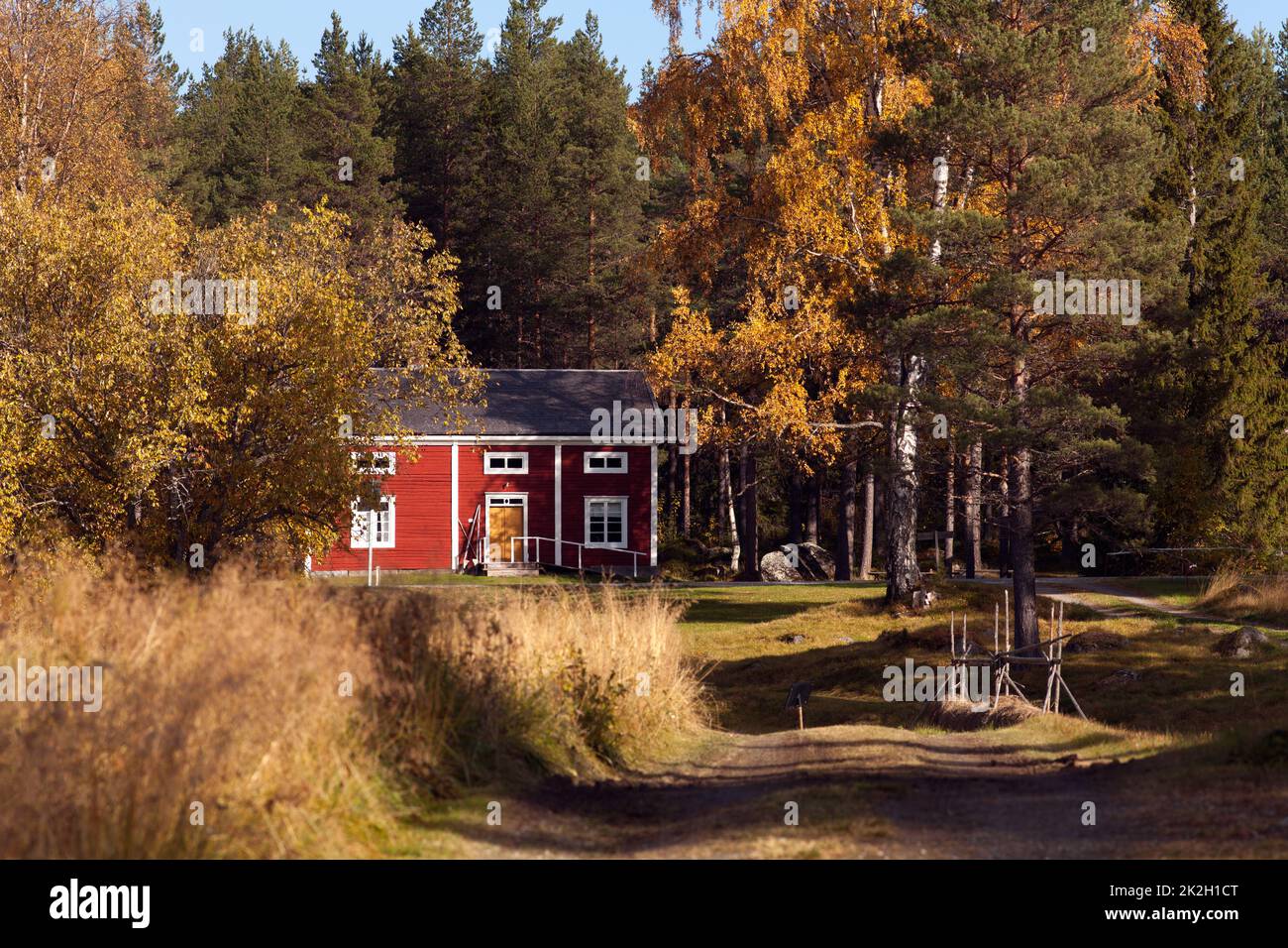 A red wooden building in rural countryside. Farmhouse behind a small ...