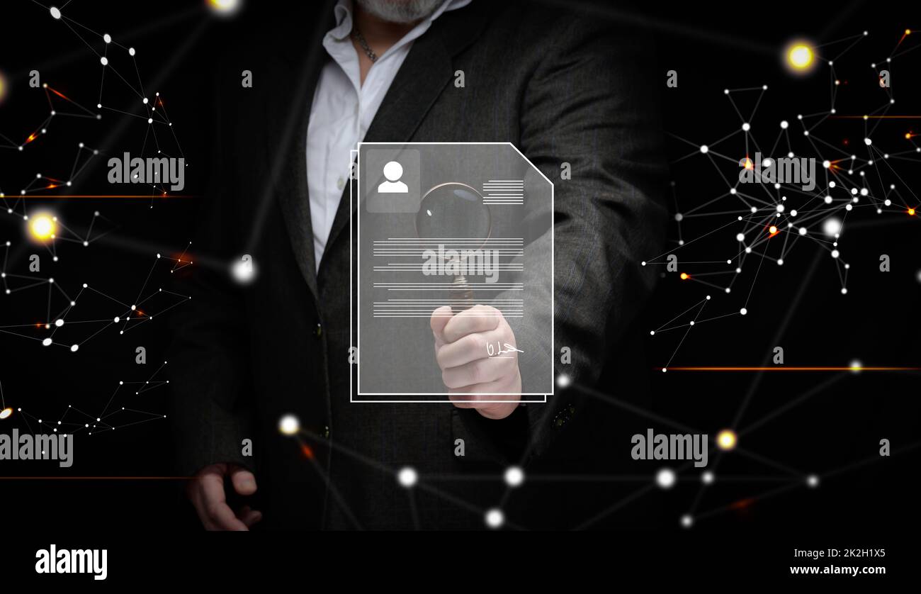 a businessman in a suit stands with a magnifying glass and examines the ...