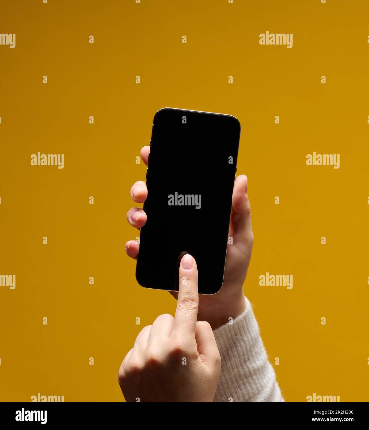 female hand holding smartphone with blank black screen on yellow ...