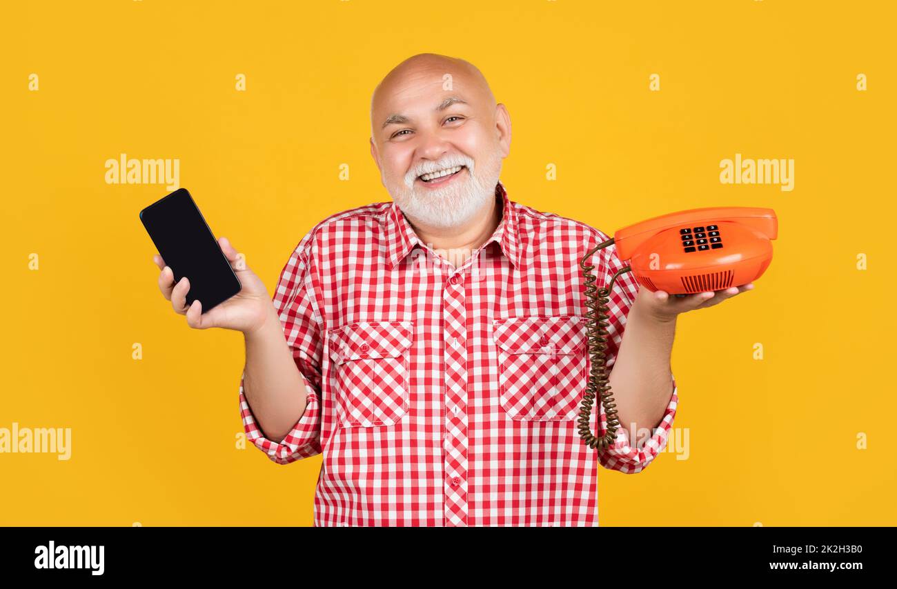 happy smiling old man with retro telephone and modern smartphone on ...