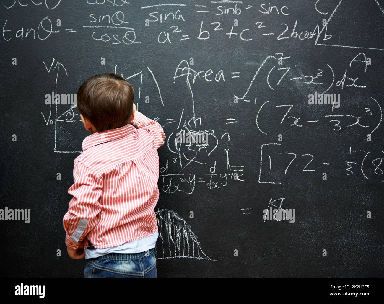 Mastering math. Shot of a young boy with a blackboard full of math ...