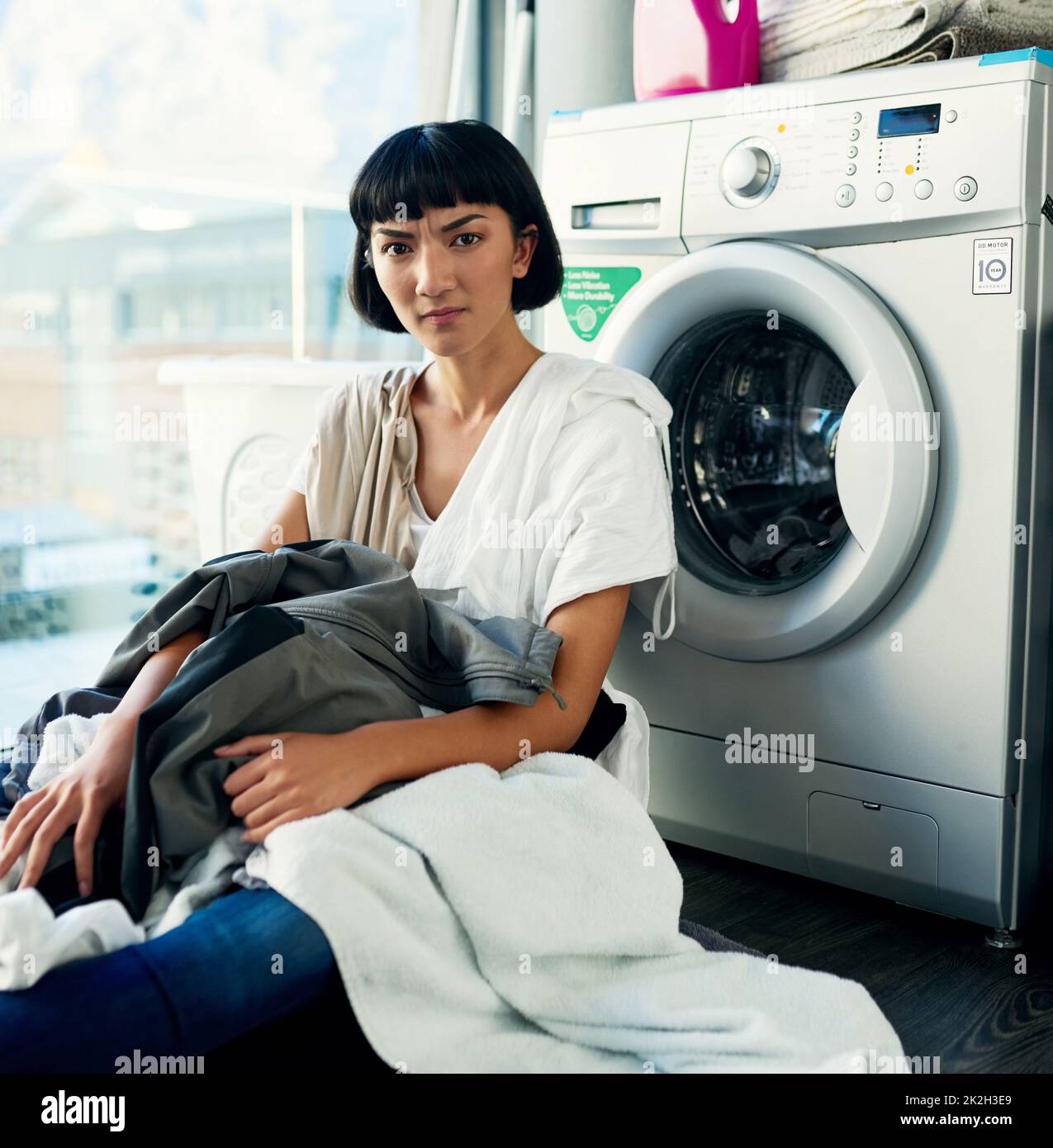 When do I get the day off. Shot of a young woman doing her laundry at ...