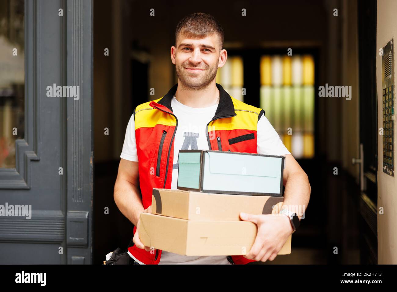 Picture of a happy delivery man with boxes in front of a door Stock ...