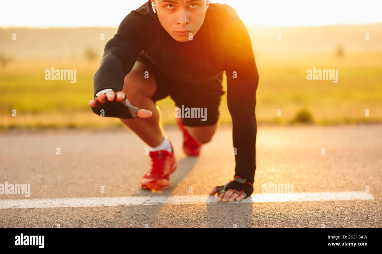 Determined male athlete standing in crouch start position and getting ...