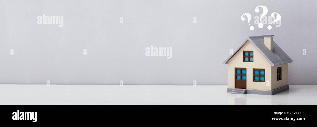 House Model With Question Marks Over Reflective Desk Stock Photo - Alamy