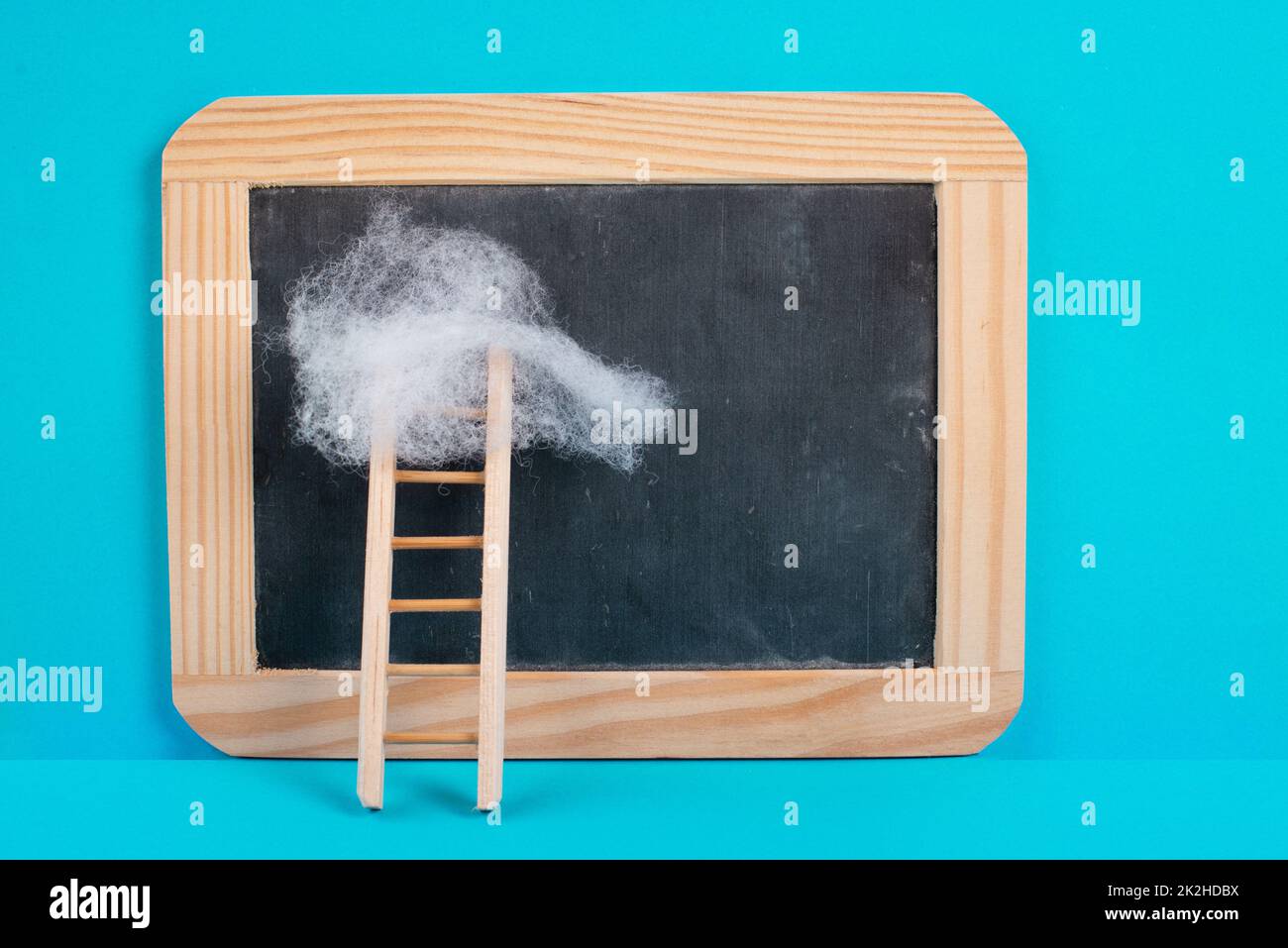 Ladder with a cloud on top, blank chalkboard, blue colored background ...