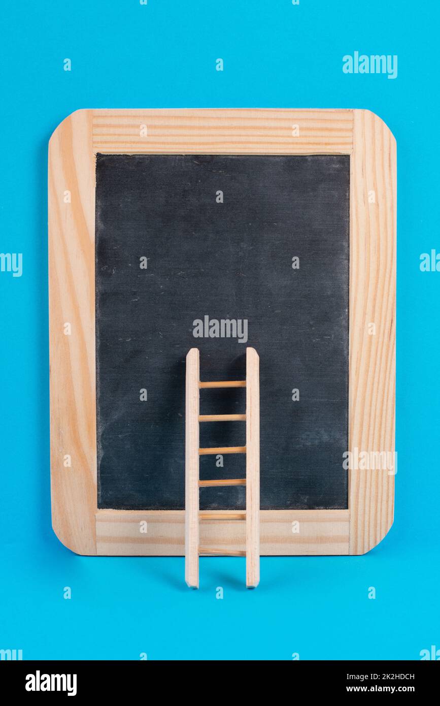 Ladder on an empty chalkboard, blue colored background, copy space ...