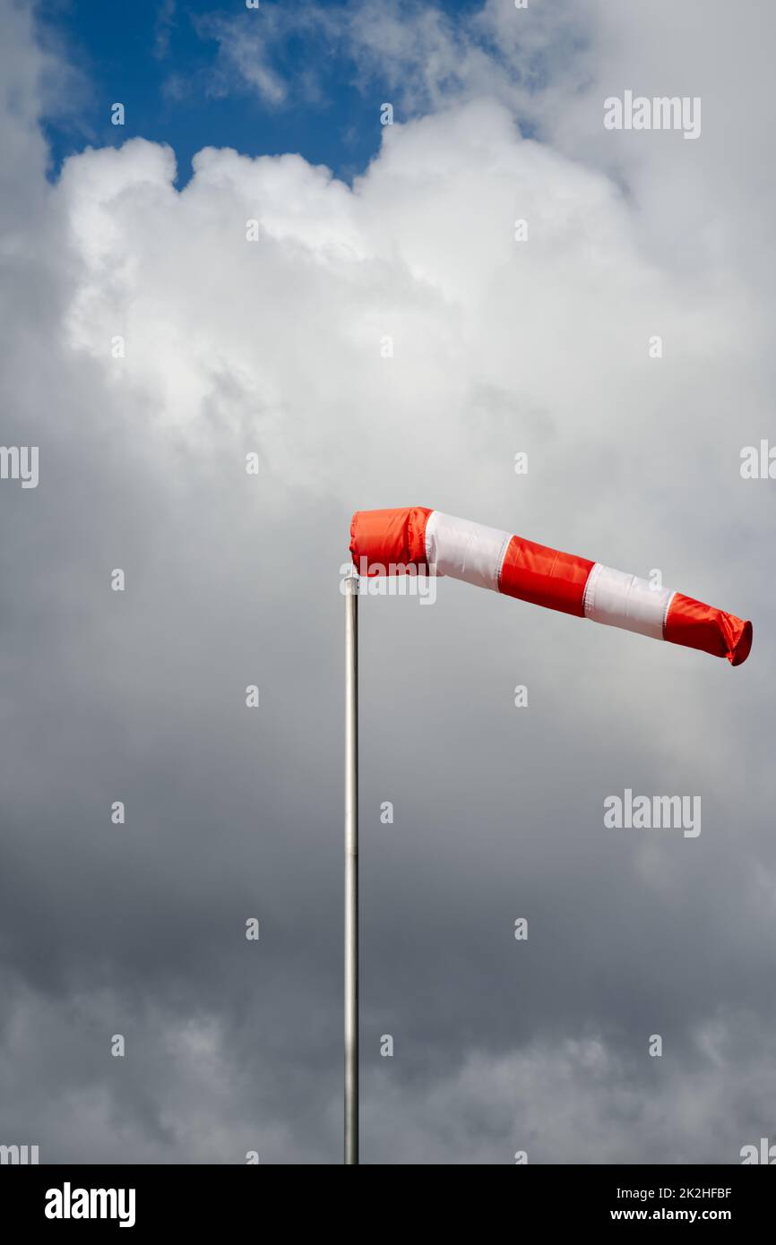 red windsock/ textile tube on a stormy sky at daytime, daylight, dark ...