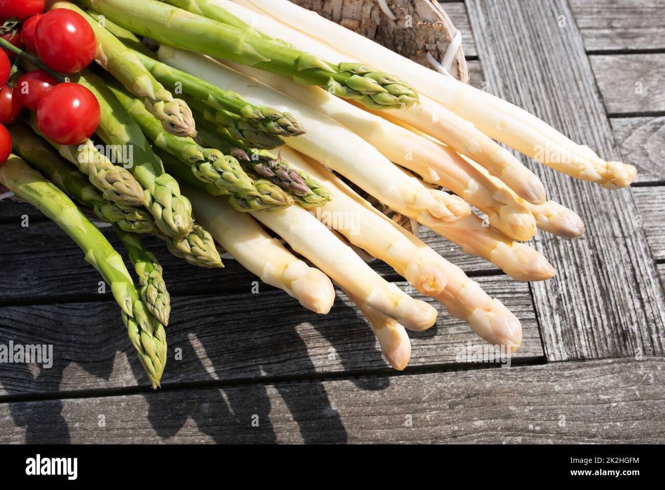 Asparagus with small tomatos on wood Stock Photo - Alamy