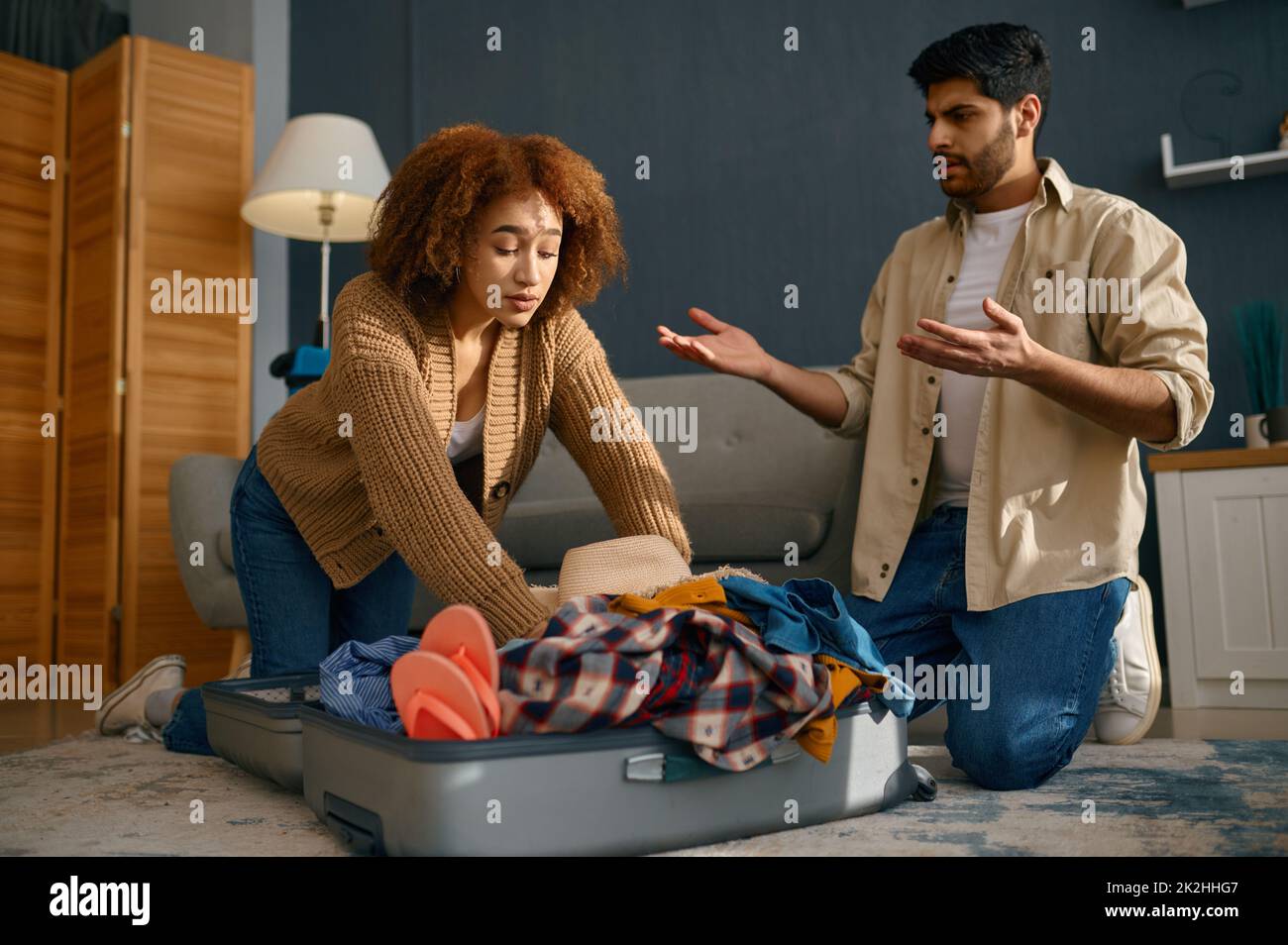 Couple trying to pack belongings into suitcase Stock Photo - Alamy