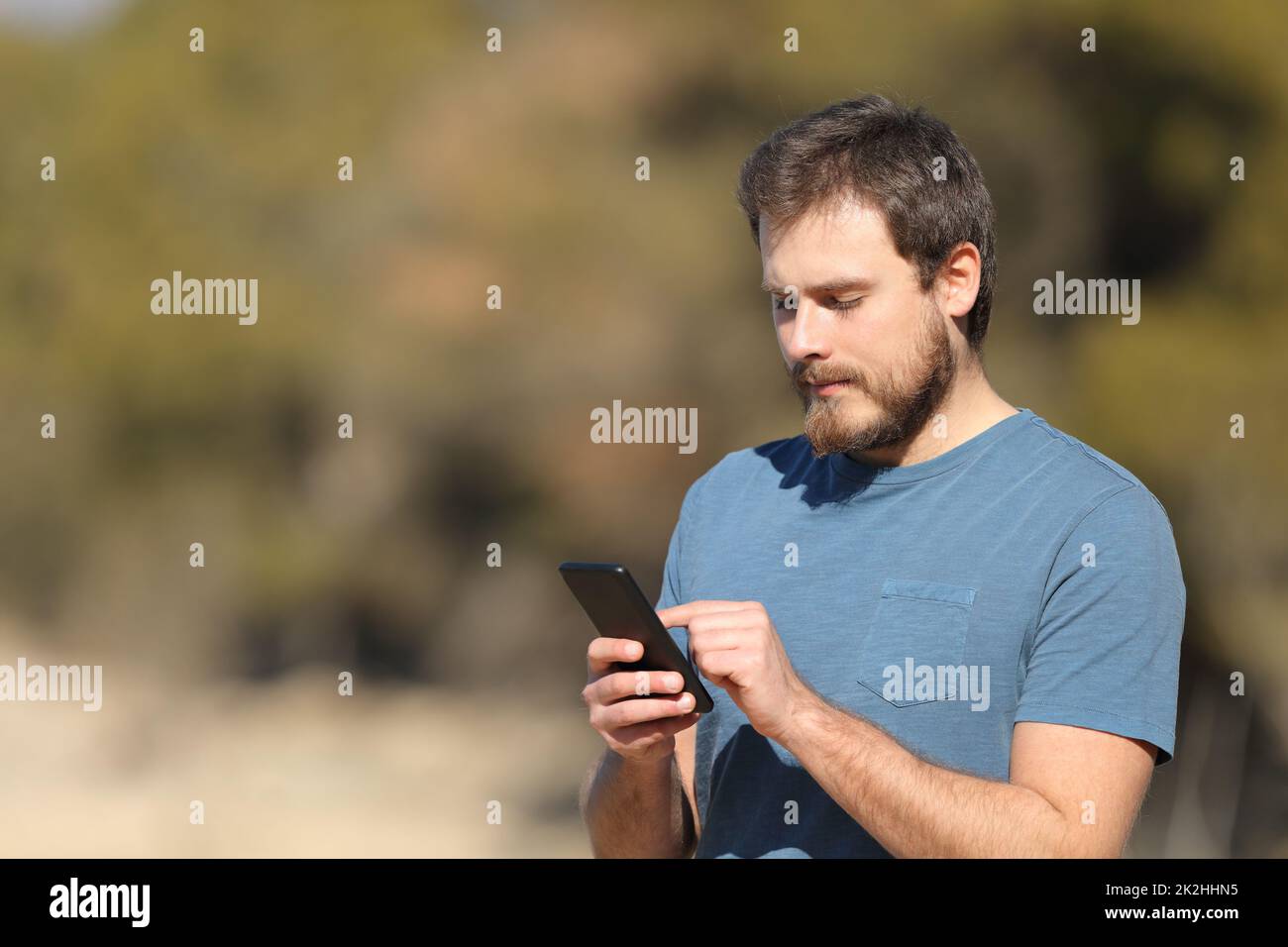 Man using smart phone standing in nature Stock Photo - Alamy