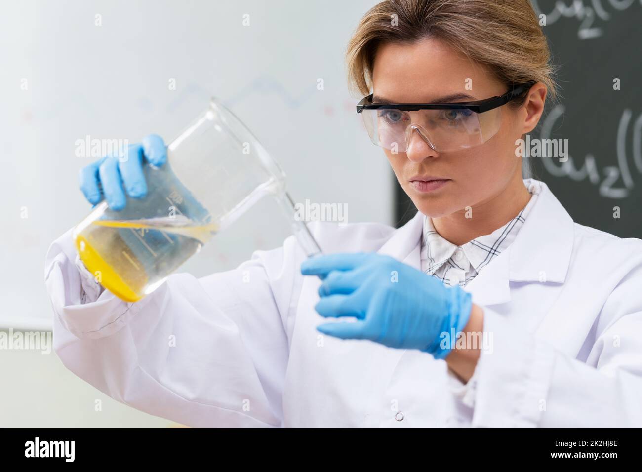 Scientist pouring substance from beaker to test tube in a laboratory ...