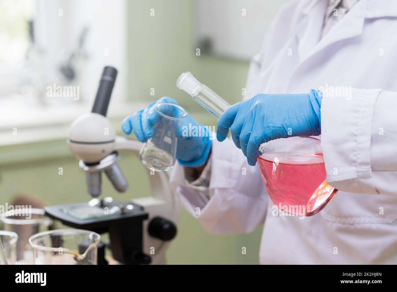 Scientist pouring pink substance from one flask to another in a laboratory Stock Photo - Alamy