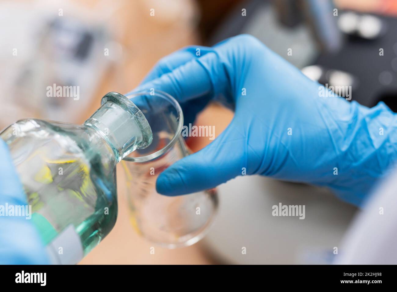 Scientist pouring substance from one flask to another in a laboratory ...