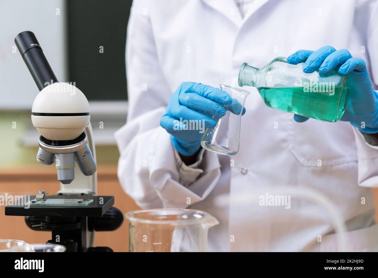 Scientist pouring substance from one flask to another in a laboratory Stock Photo - Alamy