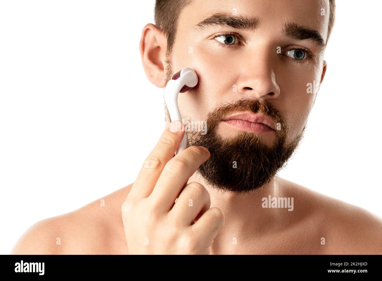Handsome man using meso roller for better beard growth Stock Photo - Alamy