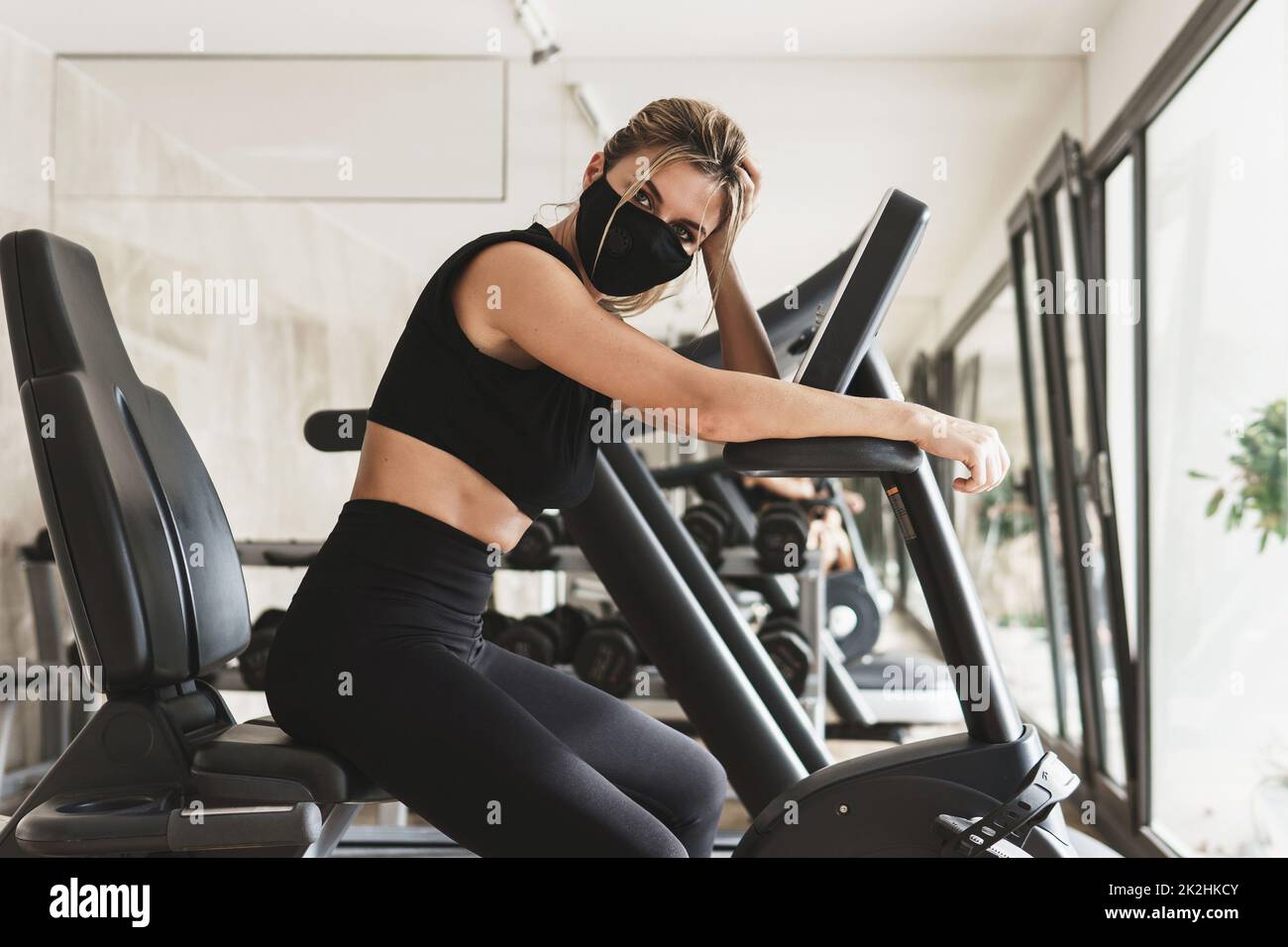Young athletic woman wearing a prevention face mask during her fitness ...