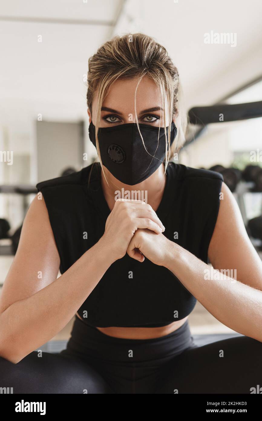 Young athletic woman wearing a prevention face mask during her fitness ...