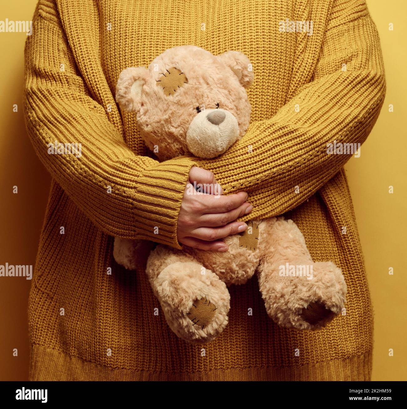 woman in orange knitted sweater hugs cute brown teddy bear. The concept ...