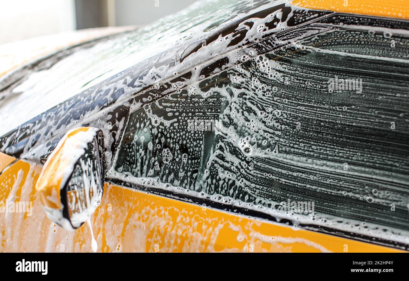Side window and mirror of yellow car washed in carwash. Strokes from ...