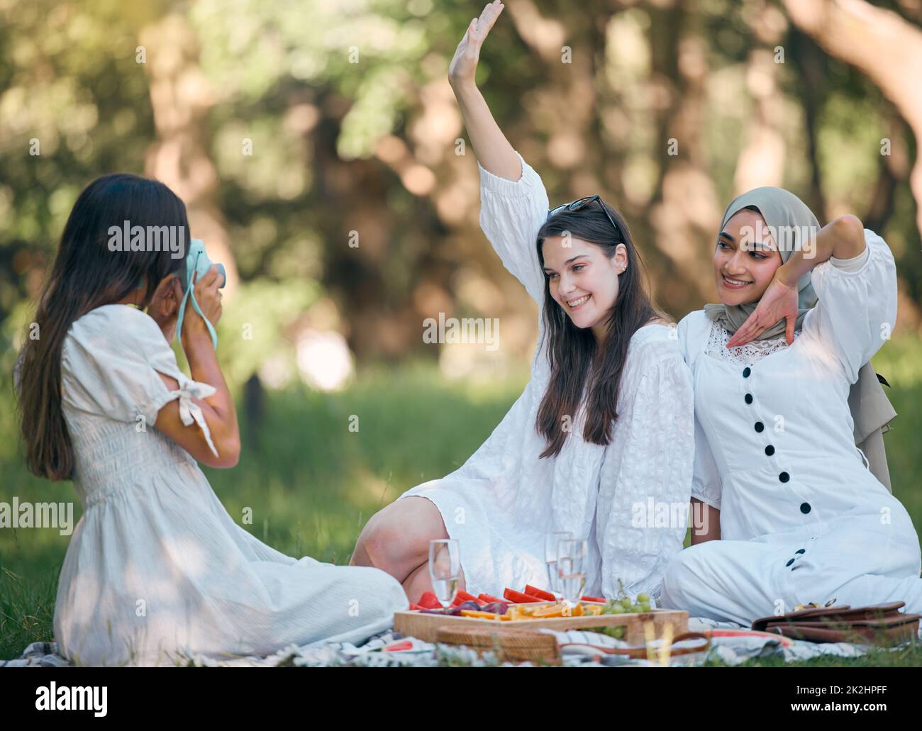 Friends, camera and photo on a picnic in a forest with food and drinks ...