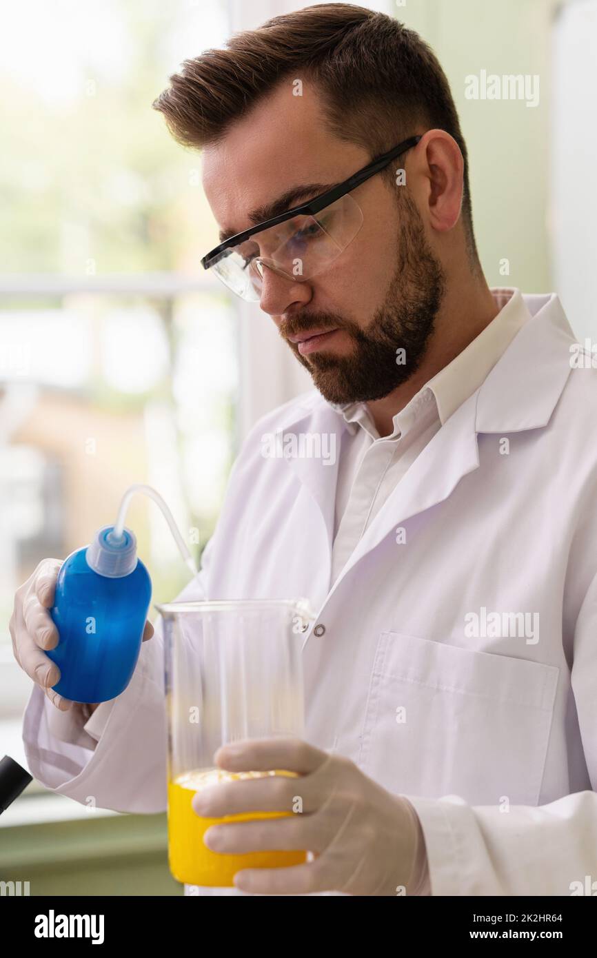 Scientist pouring water into the beaker in a laboratory during research ...