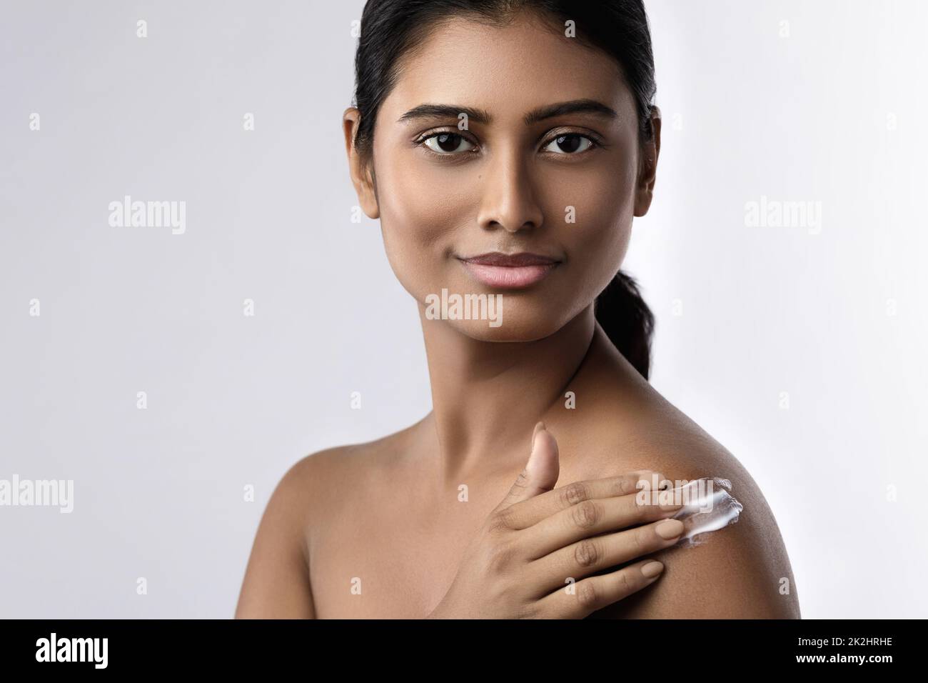 Beautiful Indian woman applying moisturizing cream or sunblock lotion ...