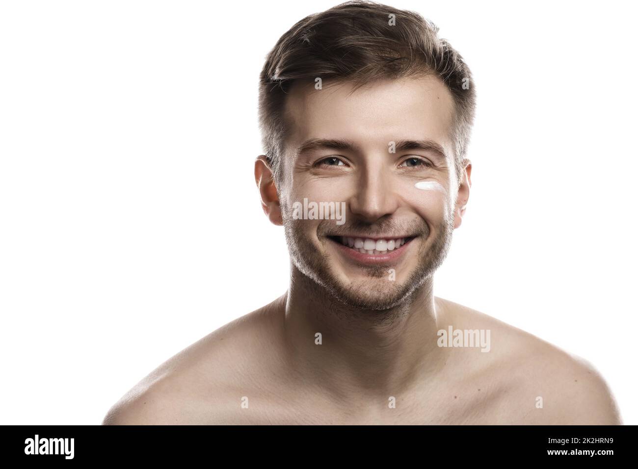 Men's beauty. Young man is applying moisturizing and anti aging cream ...