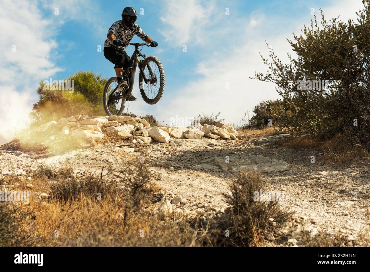 Professional bike rider jumping during downhill ride on his bicycle ...