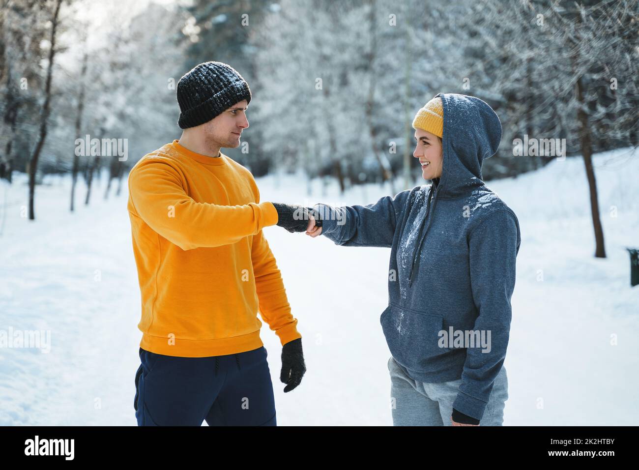 Two joggers greeting each other with a fist bump gesture during winter ...