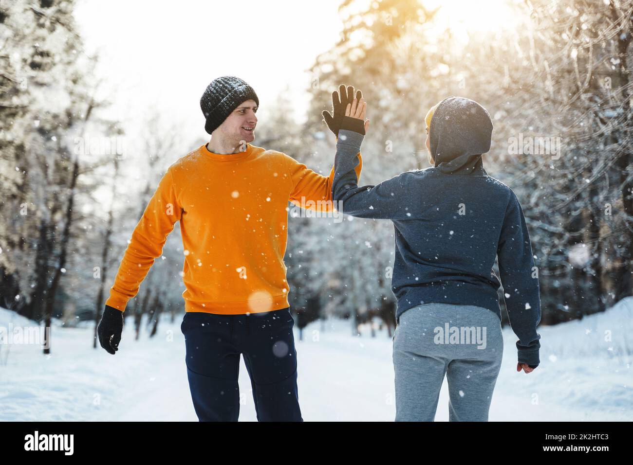 Two joggers greeting each other with a high five gesture during winter ...