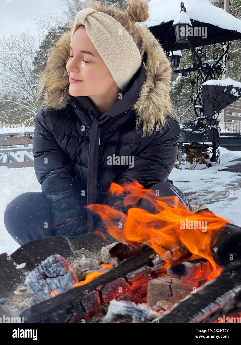 Young woman warming up by the fire pit during cold winter day Stock ...