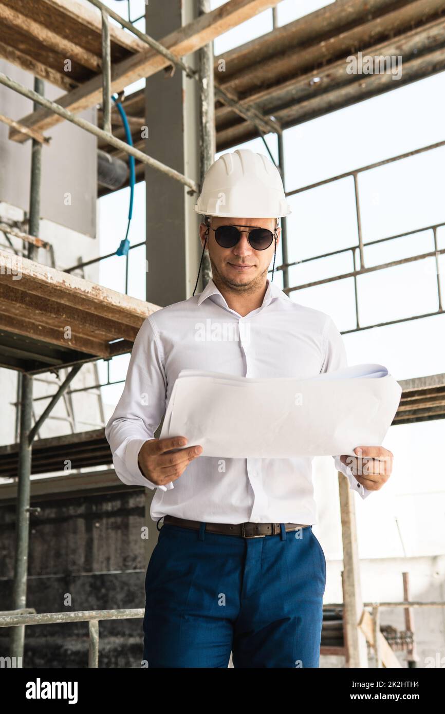 Man architect or businessman wearing hard hat and holding blueprints on ...