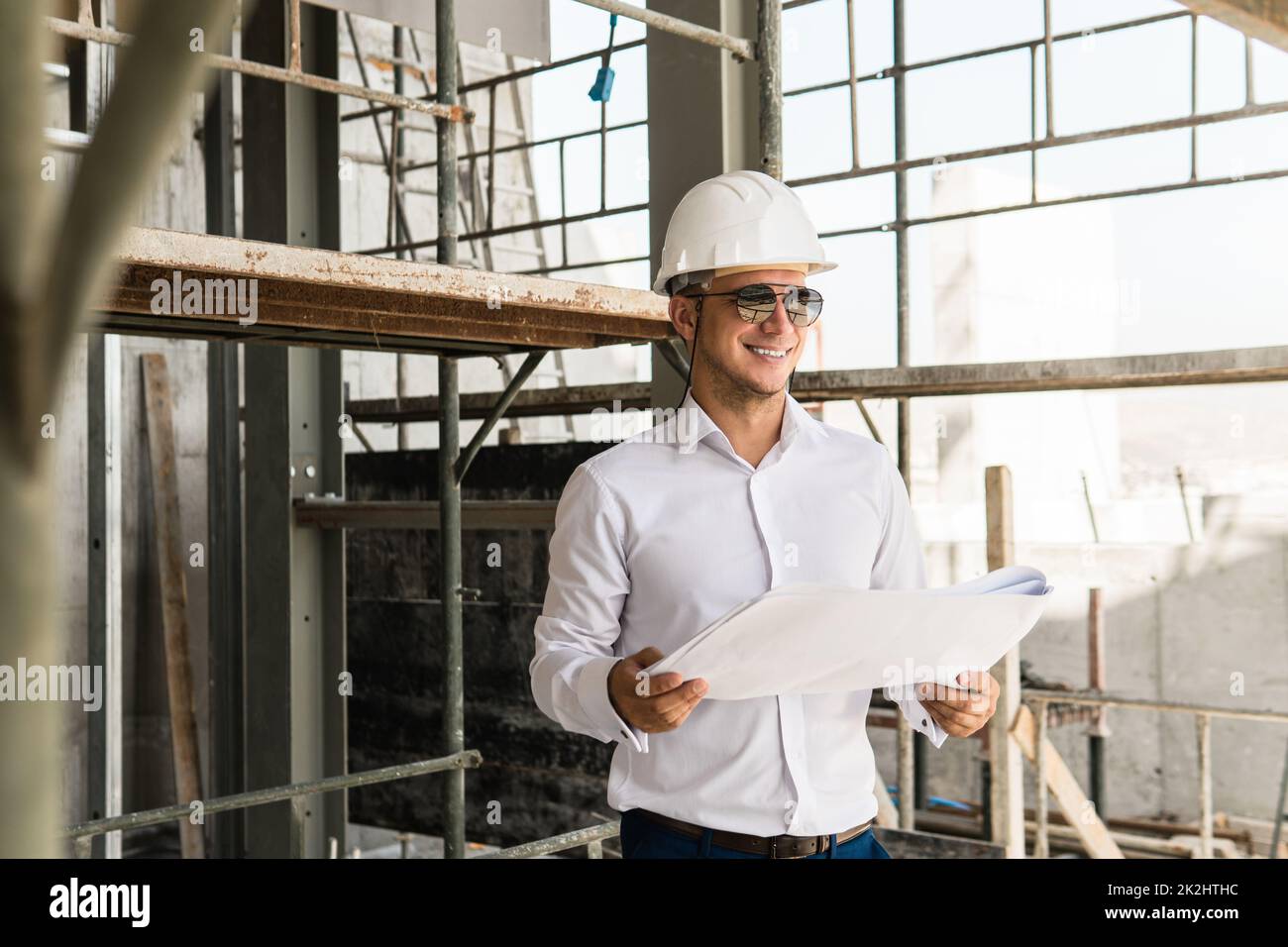 Man architect or businessman wearing hard hat and holding blueprints on ...