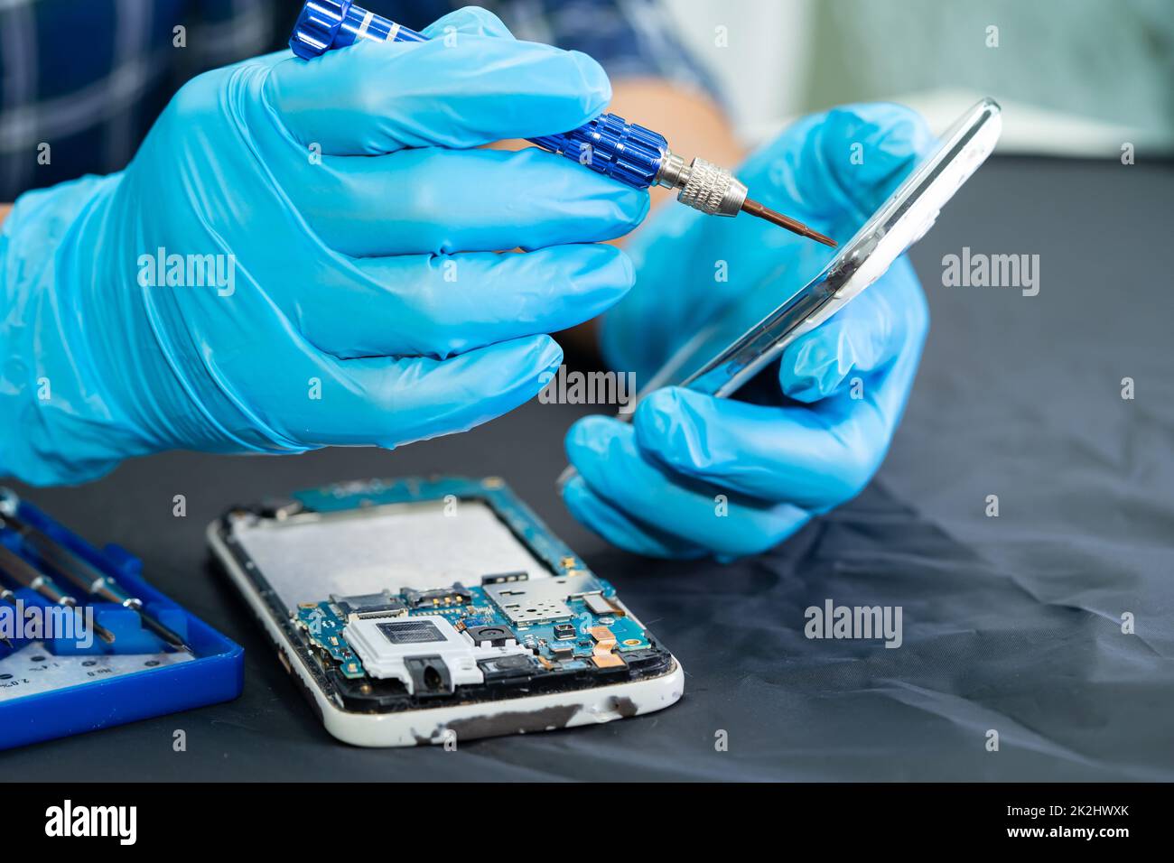 Technician repairing inside of mobile phone by soldering iron ...